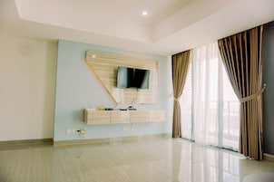 Uma sala de estar moderna com uma TV de tela plana presa a um painel de madeira, um armário embutido abaixo e uma grande janela com cortinas.