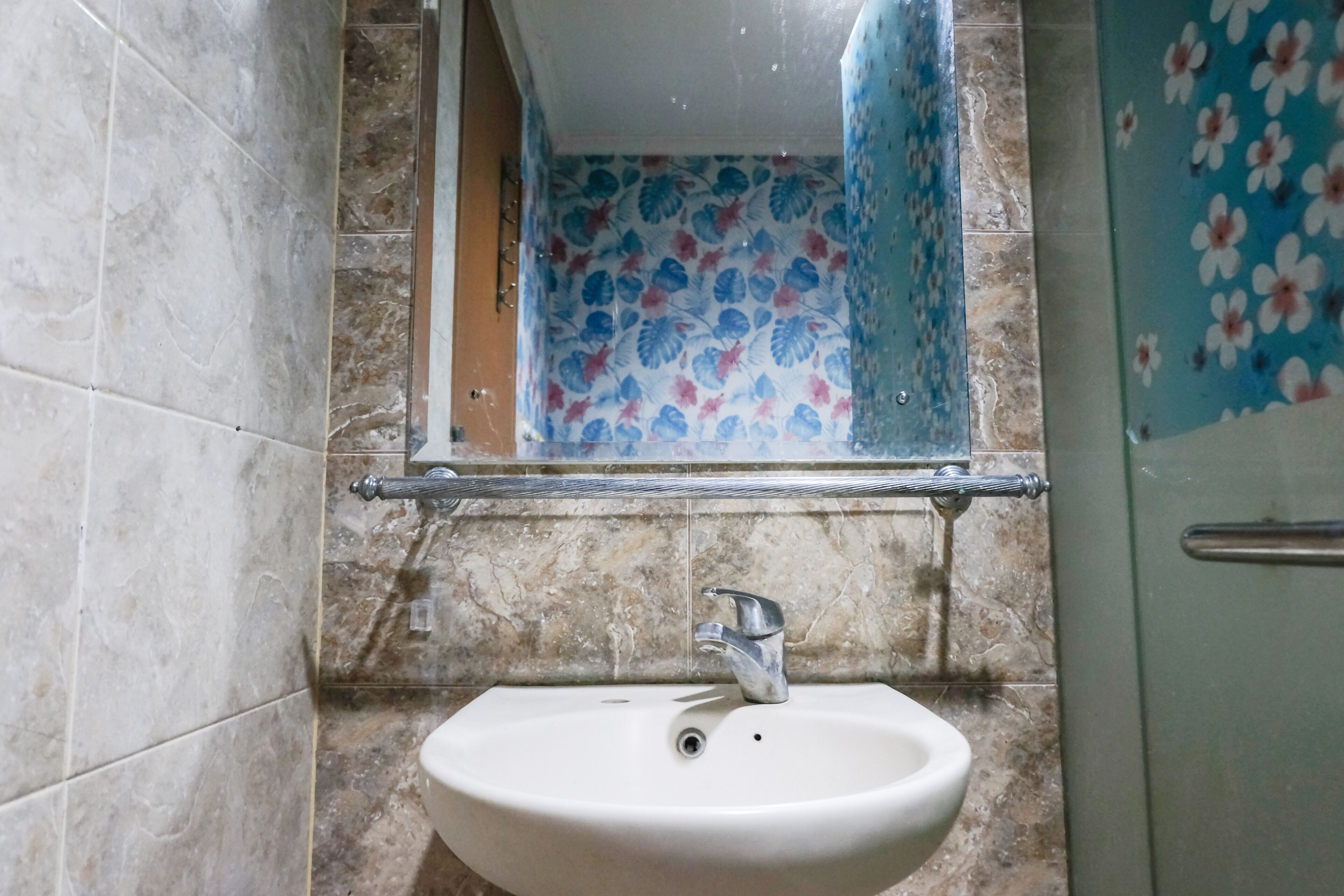 Casa de banho com lavatório, espelho e paredes revestidas a azulejos.