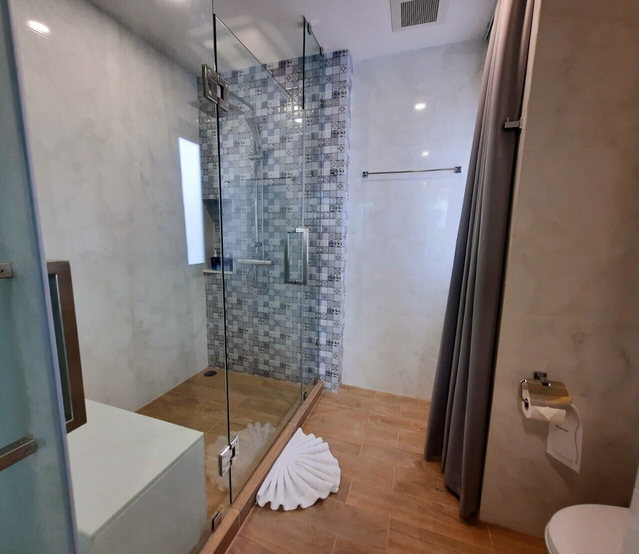 Um banheiro moderno com chuveiro em cabine de vidro, pia branca e vaso sanitário.
