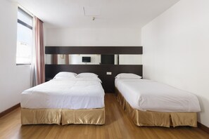 Quarto de hotel com duas camas de solteiro, um espelho grande, uma televisão de tela plana e uma janela com cortinas.