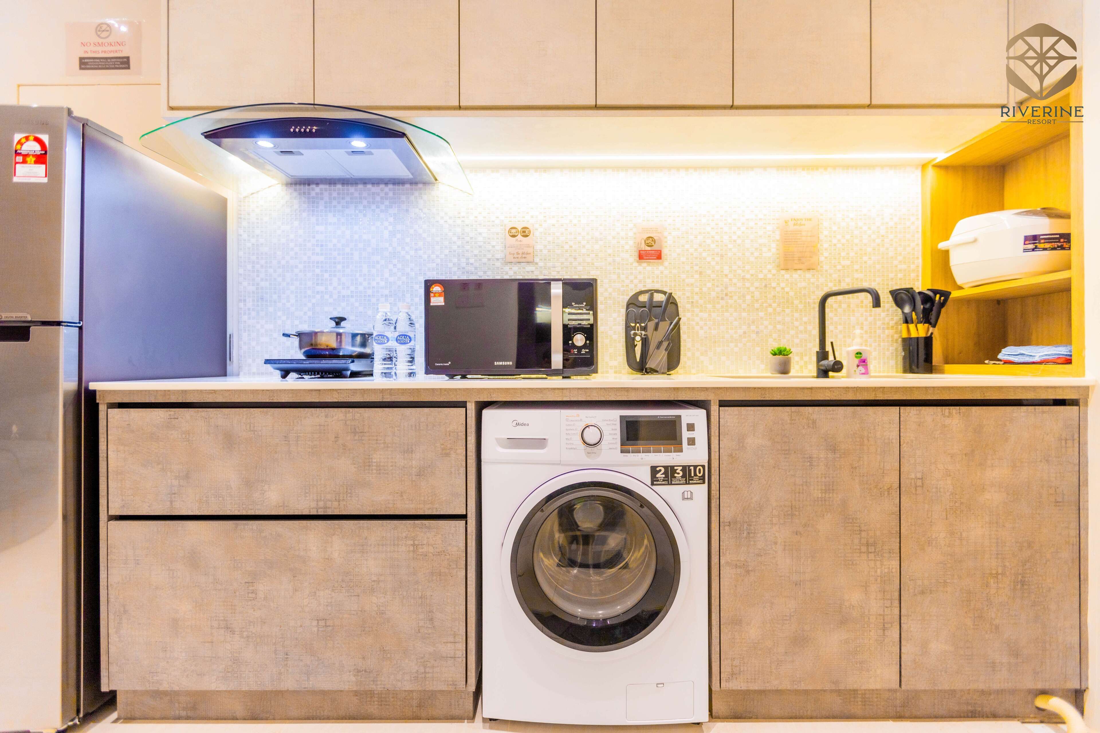 Cozinha compacta com máquina de lavar, micro-ondas e frigorífico.