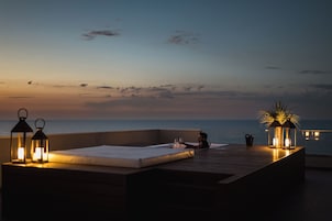 Terraço no telhado com vista para o mar, equipado com assentos e lanternas.