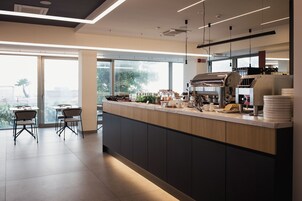 Um café moderno com um balcão extenso, área de estar e grandes janelas.