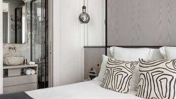 Um quarto moderno com uma cama grande, uma mesa de cabeceira com espelho e uma luminária fixada na parede.