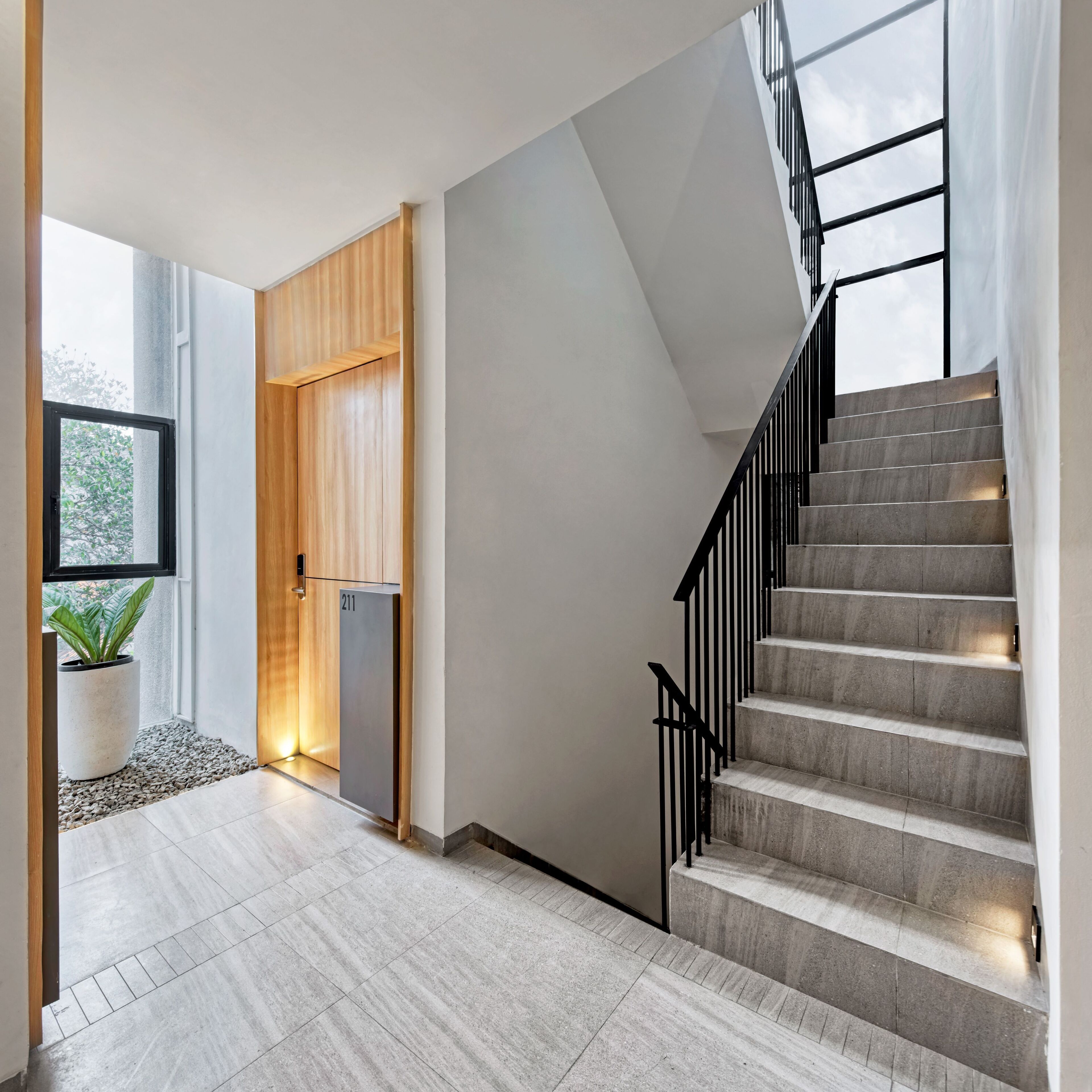 Um interior moderno com escada, porta de madeira e planta em vaso.