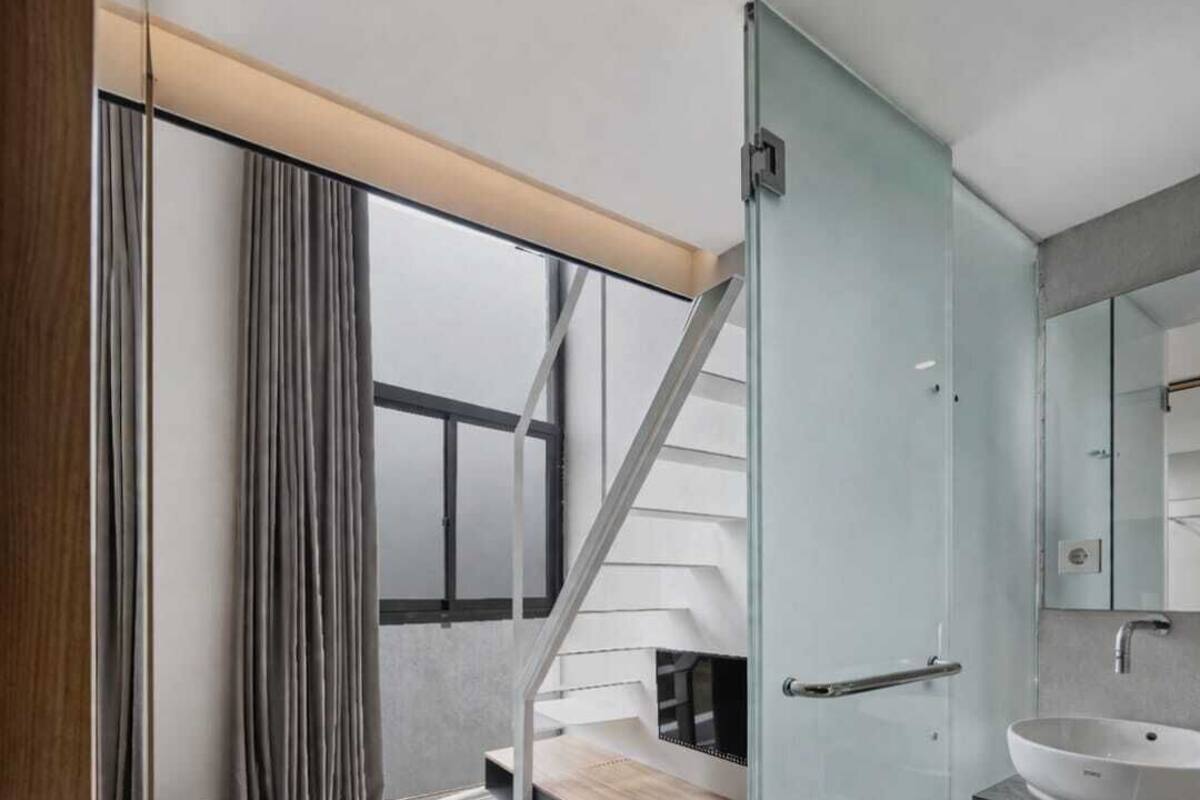 Uma casa de banho moderna com cabine de duche em vidro, um banco embutido e um espelho grande sobre a pia.