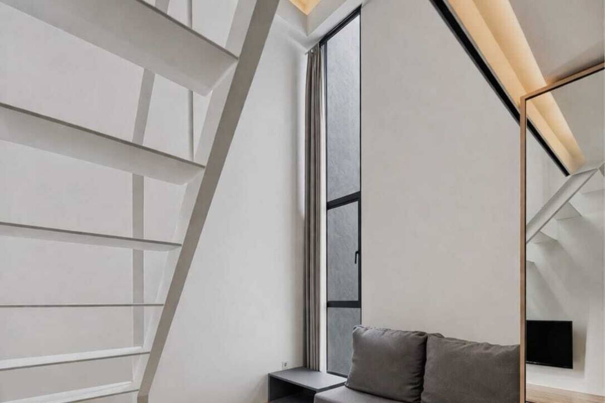 Um interior moderno com escada, sofá e televisão.