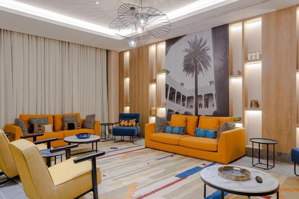 Uma sala de estar moderna com dois sofás laranja, uma poltrona amarela e uma mesa de centro.