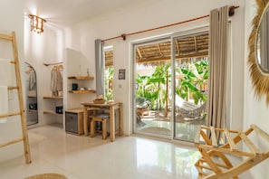 Quarto com escrivaninha de madeira, prateleiras, uma mesa pequena, cadeira e rede.