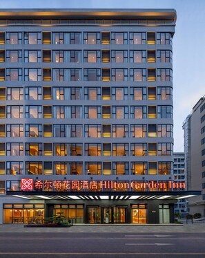 Um hotel com vários andares e fachada moderna, com destaque para a sinalização da Hilton Garden Inn.