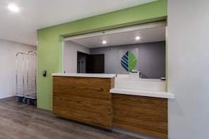 Uma mesa de recepção com design em painel de madeira, um espelho e um logotipo na parede.