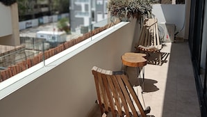 Uma varanda com um banco de madeira, uma mesa pequena e um vaso com planta.