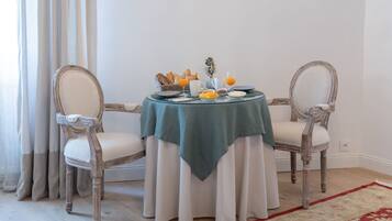 Uma mesa de jantar com toalha verde, duas cadeiras e uma disposição para café da manhã, incluindo pão, ovos e suco de laranja.