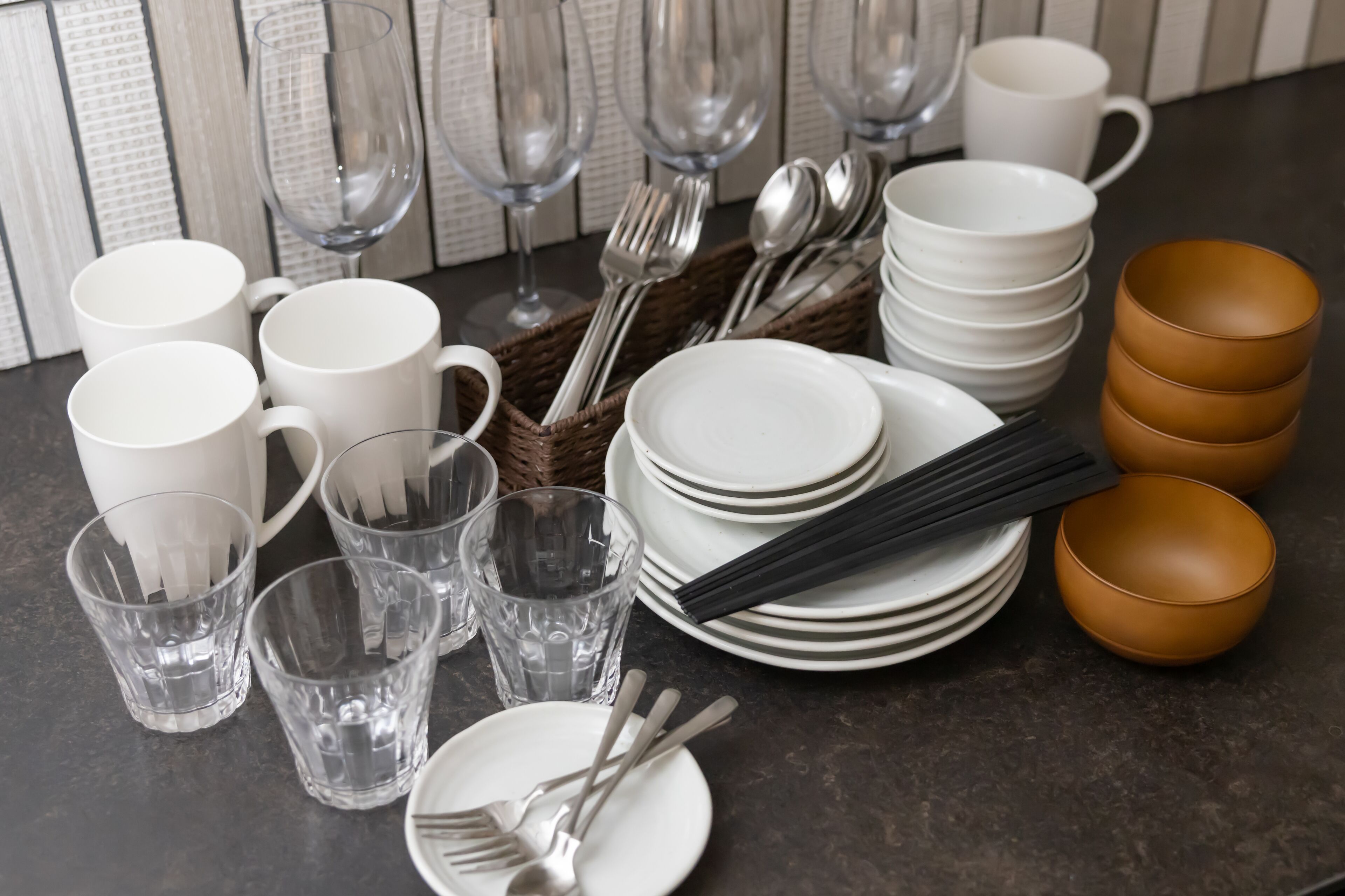 Uma mesa posta com pratos, copos e talheres brancos e castanhos.
