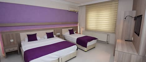 Quarto de hotel com duas camas, televisão e janela com persianas.
