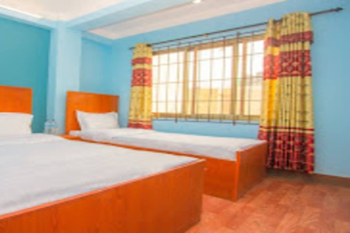 Quarto com duas camas, janela com cortinas e parede azul.