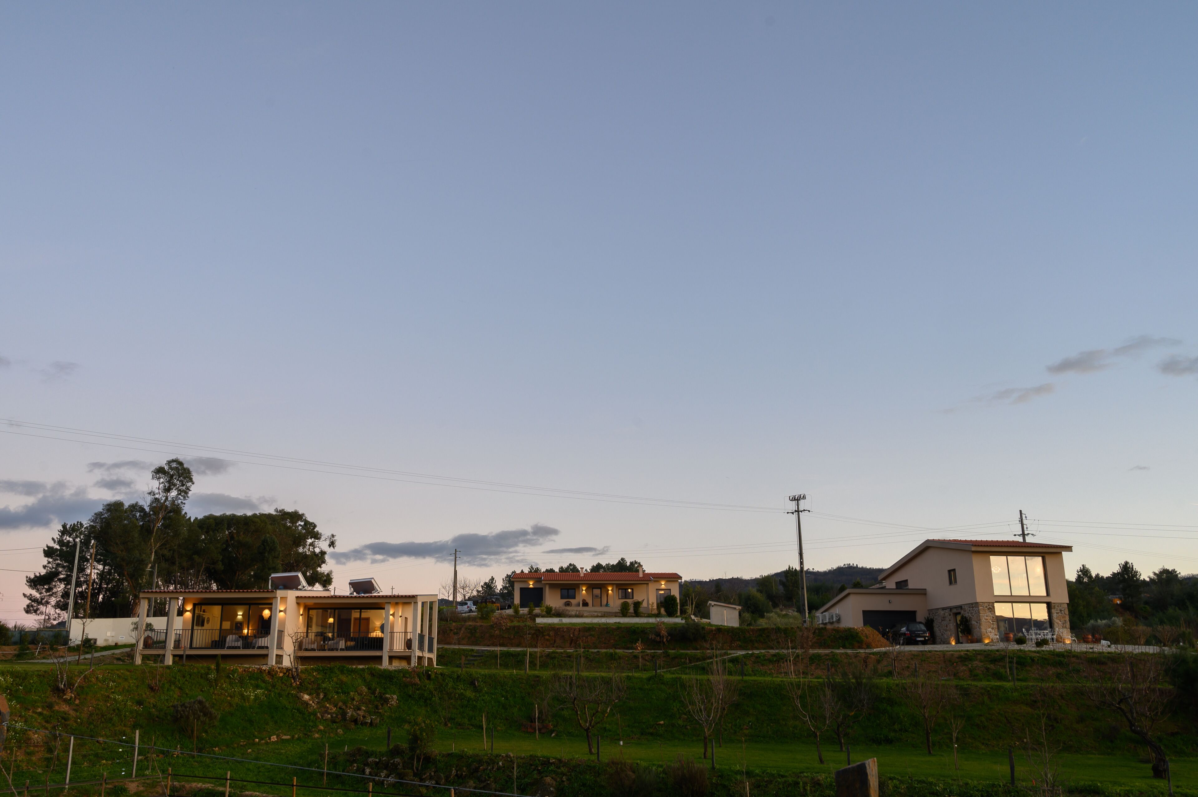 Um bairro residencial com casas, um campo cercado e céu limpo.