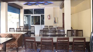 Um restaurante com um amplo espaço de refeições, várias mesas e cadeiras, e um sofá azul estampado.