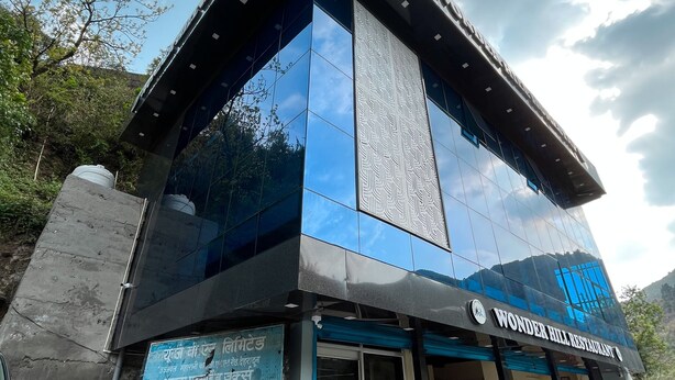 A modern building with a glass facade, a sign for "Wonder Hill Restaurant," and a staircase leading to the entrance.