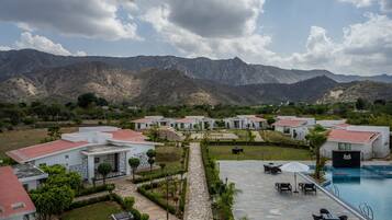 Resort com vários edifícios brancos, piscina e montanhas ao fundo.