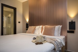 Quarto de hotel com uma cama grande, um espelho e um candeeiro fixado na parede.