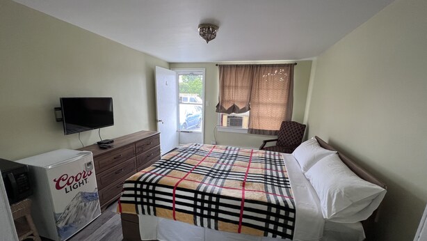 Quarto com cama, cômoda, televisão e um cooler de Coors Light.