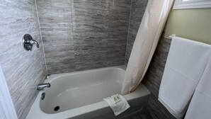 Um banheiro com banheira, cortina de chuveiro e porta-toalhas.