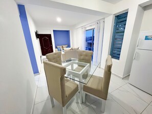 Uma sala de jantar moderna com uma mesa de vidro e quatro cadeiras bege.
