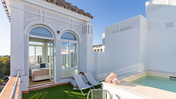 Uma área moderna com piscina ao ar livre, hidromassagem, espreguiçadeiras e um espaço de estar com mesa e cadeiras.