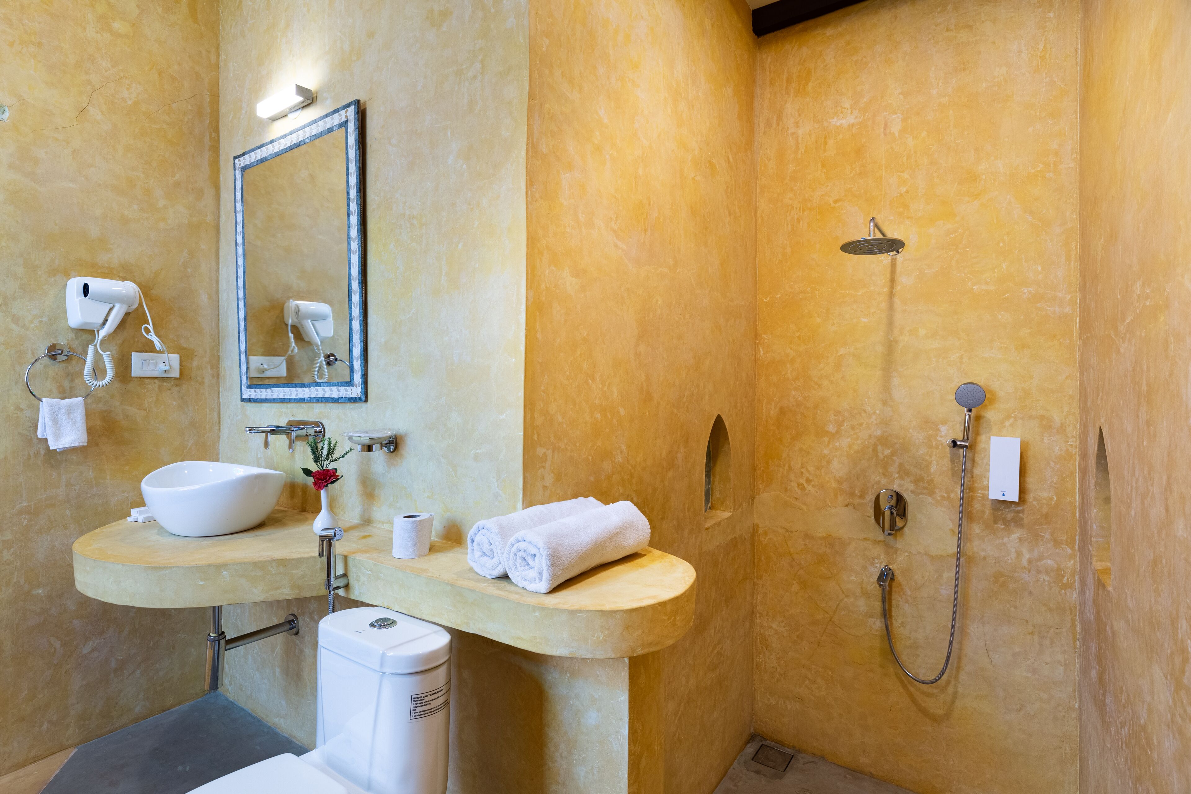 Casa de banho com lavatório, espelho, secador de cabelo, toalha e chuveiro.