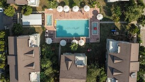 Vista aérea de um complexo residencial com várias casas, uma piscina central e áreas verdes ao redor.