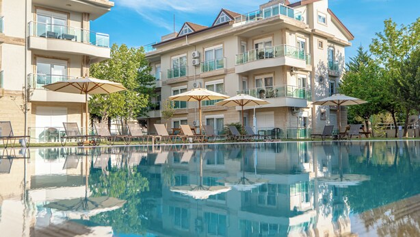 Um hotel com piscina, várias varandas e espreguiçadeiras.