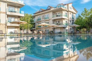 Um hotel com piscina, várias varandas e espreguiçadeiras.