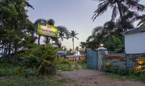 Placa para Majestic Retreat, um resort com um caminho que leva a uma entrada com portão, cercado por vegetação exuberante e palmeiras.