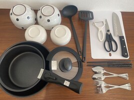 Uma cozinha equipada com panelas, utensílios e tábua de corte.