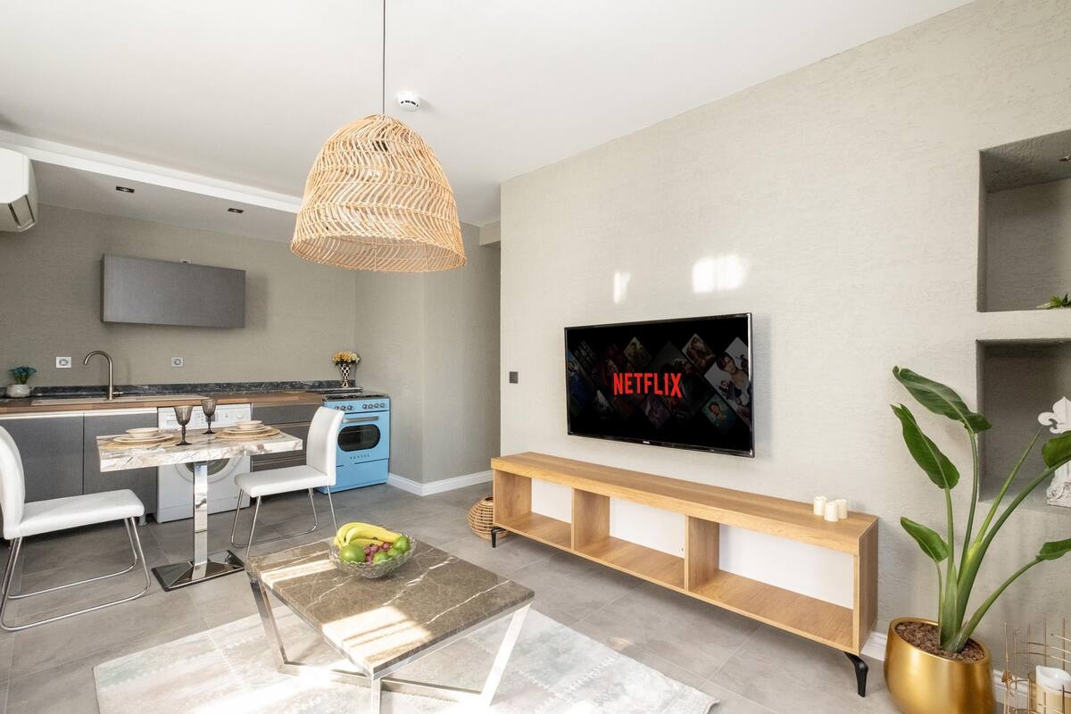 Uma cozinha moderna com área de jantar, televisão na parede e planta em vaso.