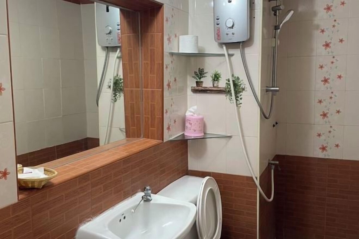 Casa de banho com lavatório, espelho, chuveiro e azulejos decorativos.