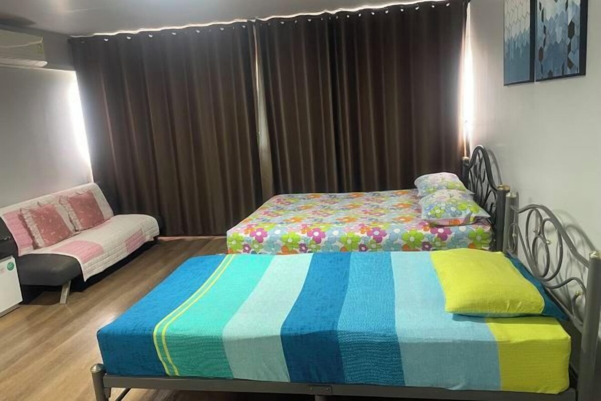 Quarto com cama, sofá e cortinas.