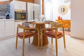 Uma cozinha moderna com armários brancos, forno embutido e área de jantar com mesa e cadeiras de madeira.