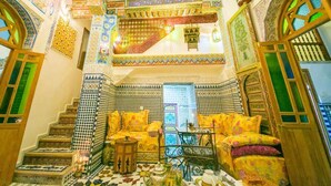 Um interior com vários níveis, detalhes em azulejos ornamentados, uma escadaria e áreas de estar.