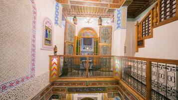 Interior ornamentado com trabalhos em azulejos detalhados, uma varanda com grade de ferro forjado e um teto ricamente decorado.