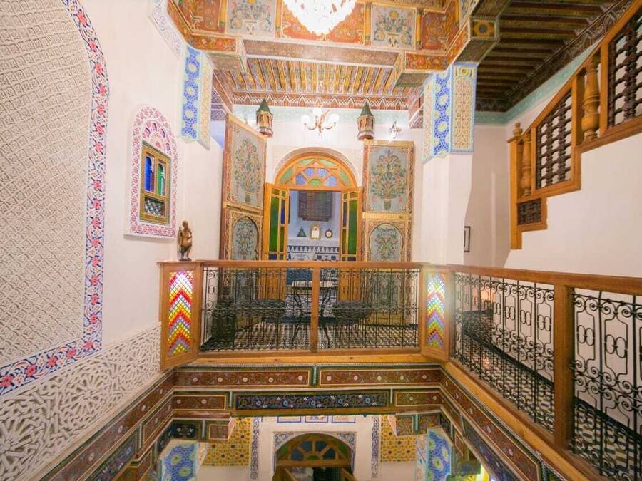 Interior ornamentado com trabalhos em azulejos detalhados, uma varanda com grade de ferro forjado e um teto ricamente decorado.
