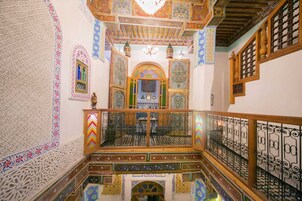 Interior ornamentado com trabalhos em azulejos detalhados, uma varanda com grade de ferro forjado e um teto ricamente decorado.