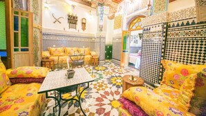 Um quarto com piso estampado, um sofá, uma mesa e uma parede decorativa.