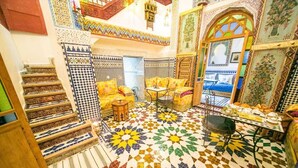 Quarto com piso estampado, escada e área de jantar com cadeiras amarelas e mesa posta para refeição.