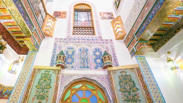 Um interior com trabalhos de azulejos ornamentados e coloridos, e detalhes em esculturas de madeira.