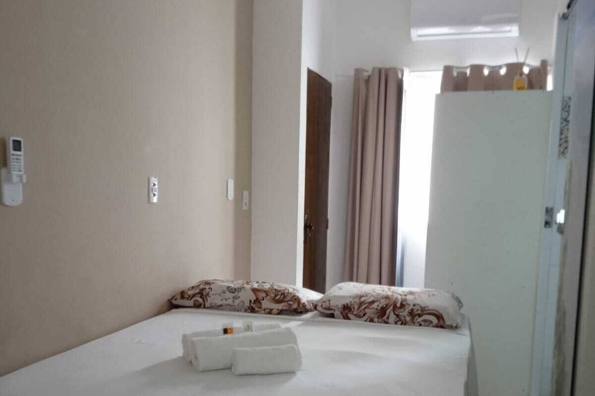 Quarto de hotel com duas camas, banheiro e armário.
