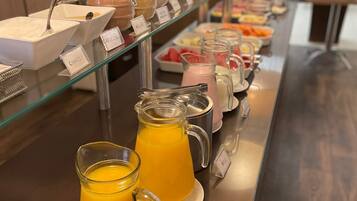 Buffet com diversas opções de comida e bebida, incluindo sucos e uma barra de saladas.