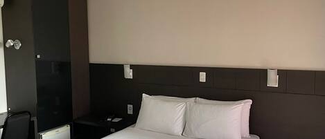 Quarto de hotel moderno com uma cama grande, uma escrivaninha e uma cadeira.