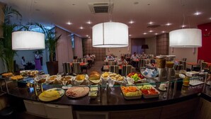 Uma área de buffet com diversos alimentos e uma área de estar ao fundo.